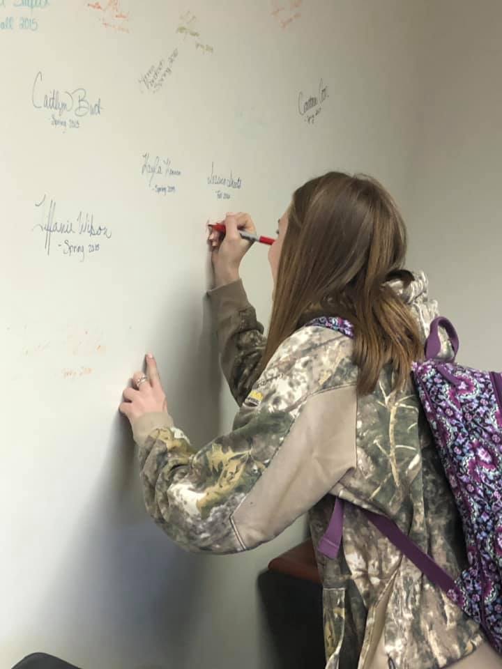 Psychology student signing lab research wall - Psychology